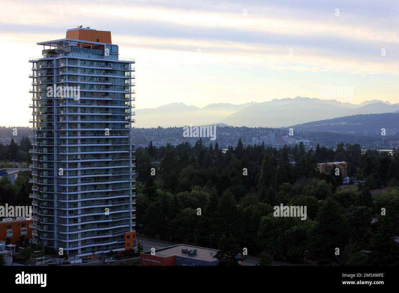 A high-rise residential building in Surrey with trees and mountains ...