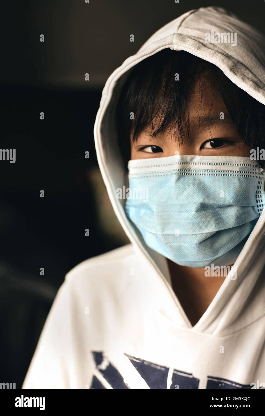 an Asian boy wearing a protective mask, looks at the camera. virus ...