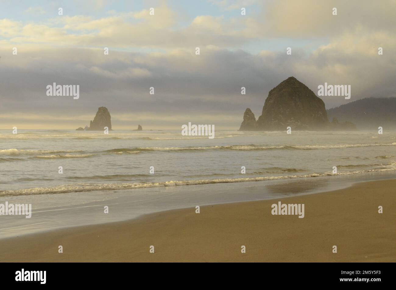 A beach of the sea with rocky mountains in the background in a fog ...