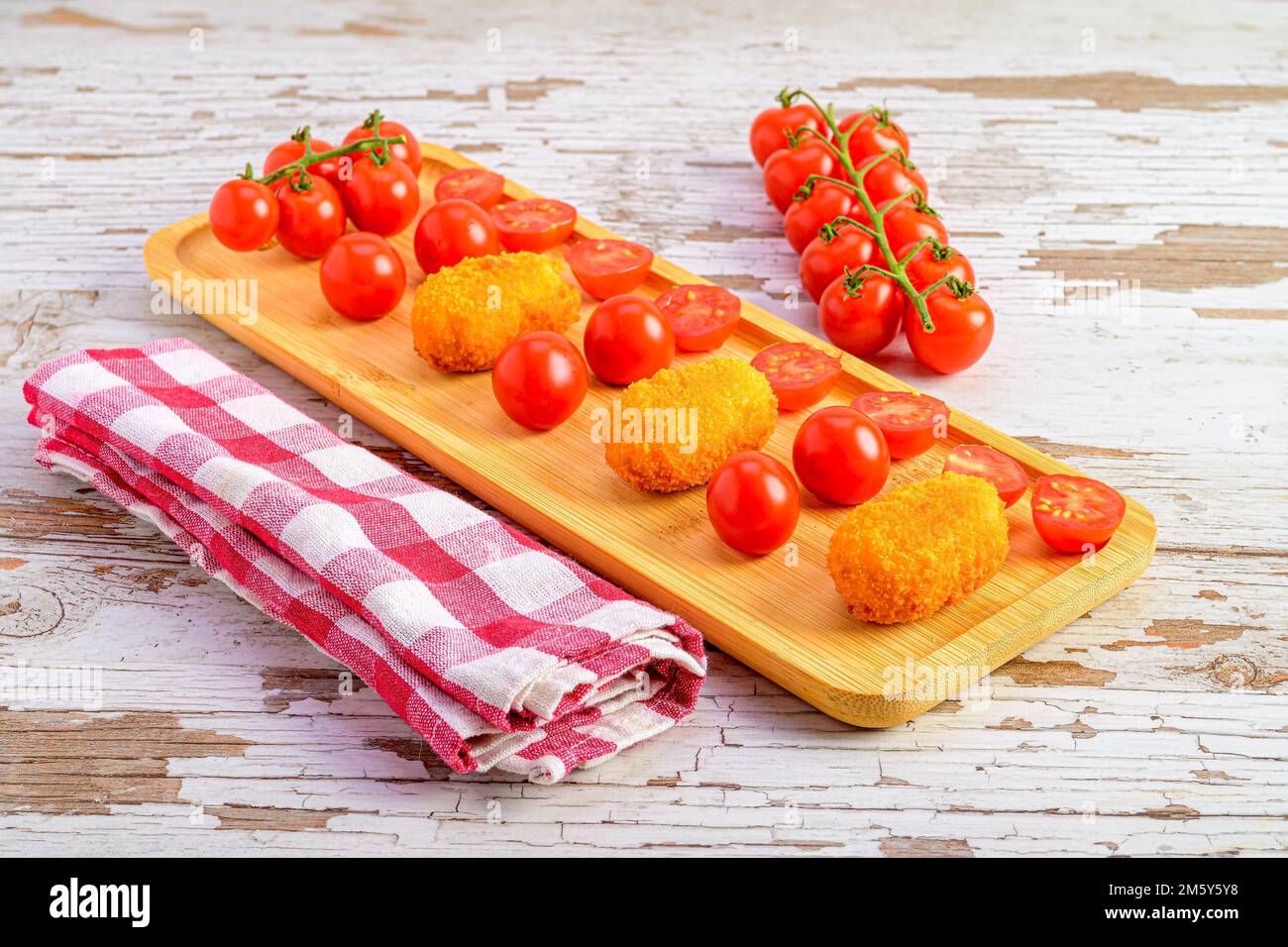 A board with cherry tomatoes and croquettes Stock Photo - Alamy
