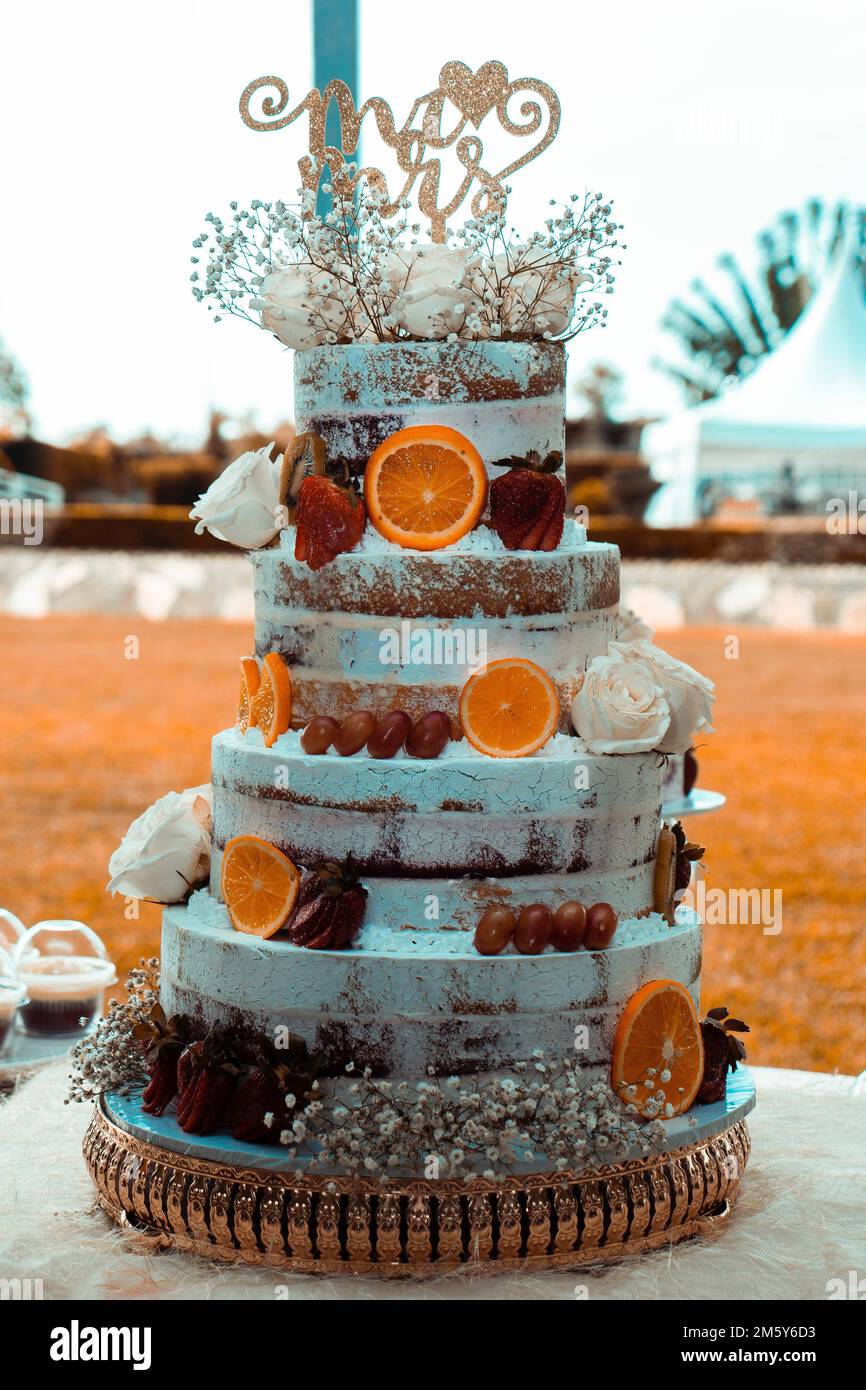 A vertical closeup of a 4-tier wedding cake decorated with fresh fruits ...