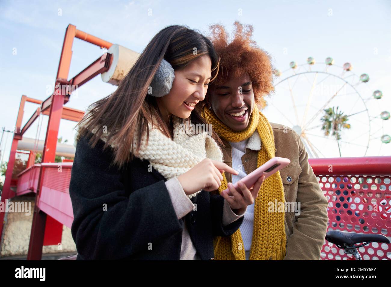 Mixed race young couple in winter clothes with cell phones outdoor ...