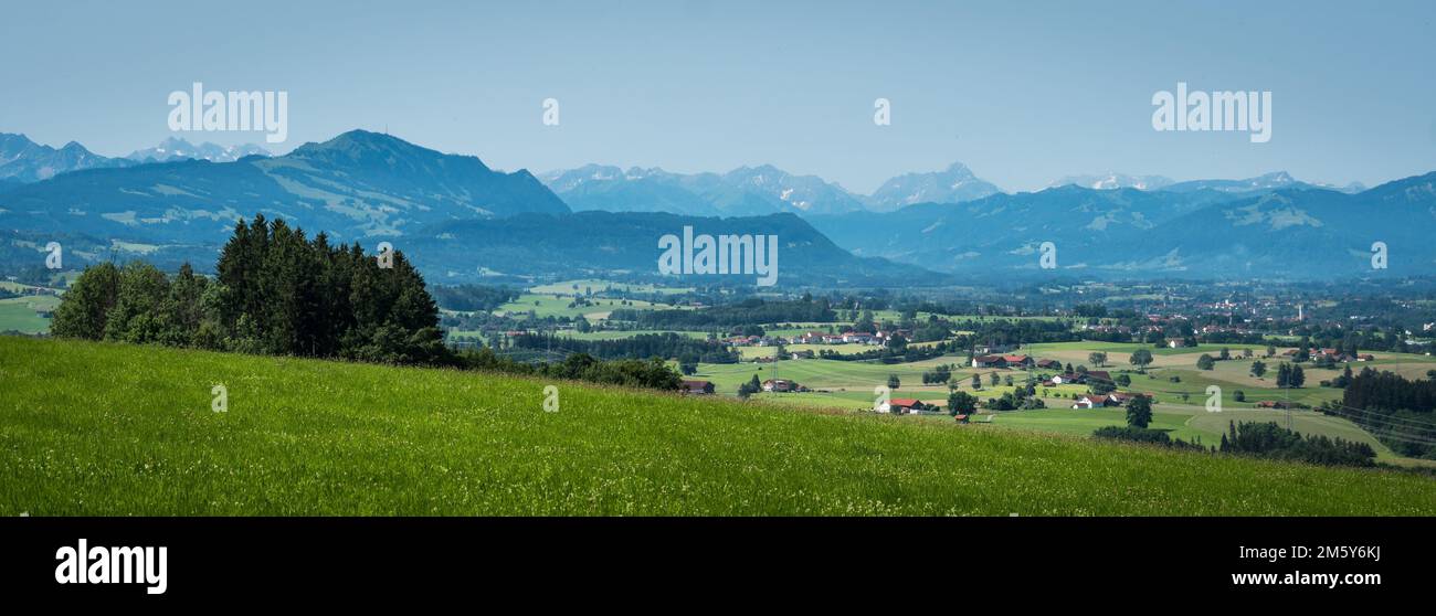 A panoramic view of a field with a village and hills in the background ...