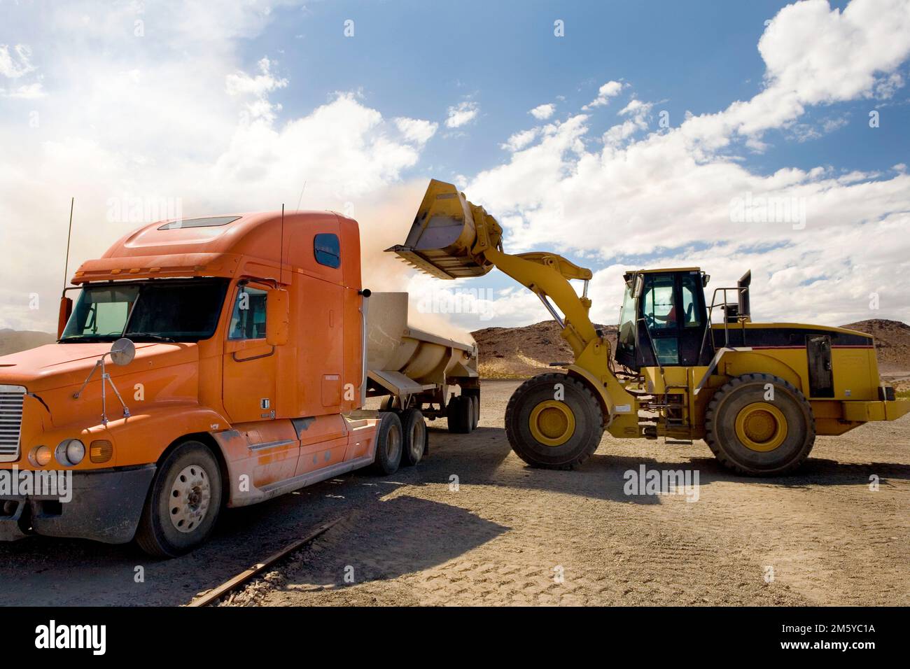 Front end loader filling a truck with sand in the California Desert ...