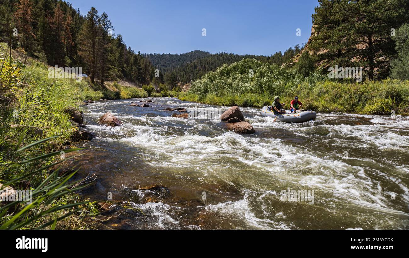 A horizontal shot of rafters on South Platte River surrounded by green ...