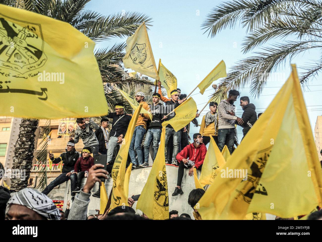 Palestinian Fatah supporters chant slogans and wave movement flags ...