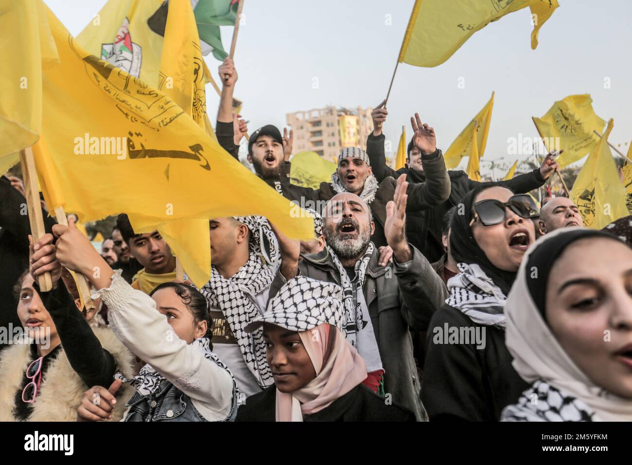 Palestinian Fatah supporters chant slogans and wave movement flags ...