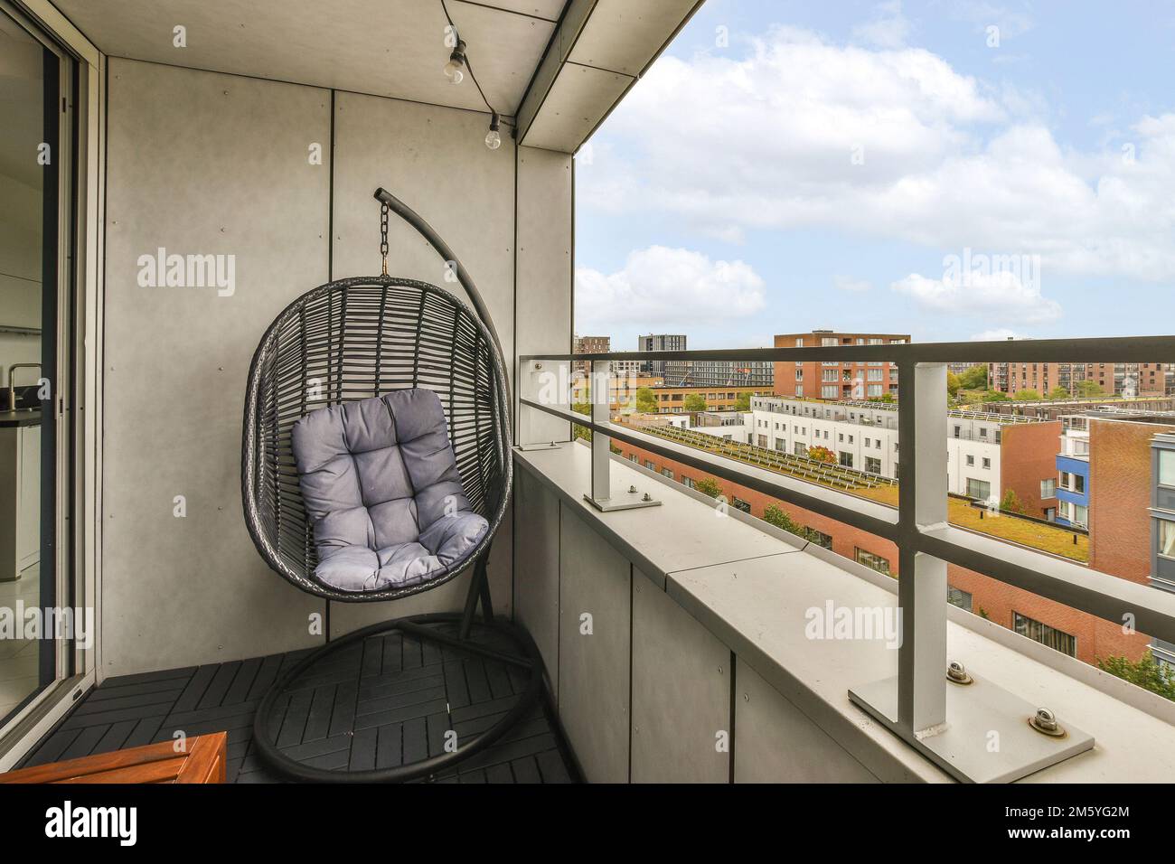 a balcony with a hanging chair on the left and a view of buildings in ...