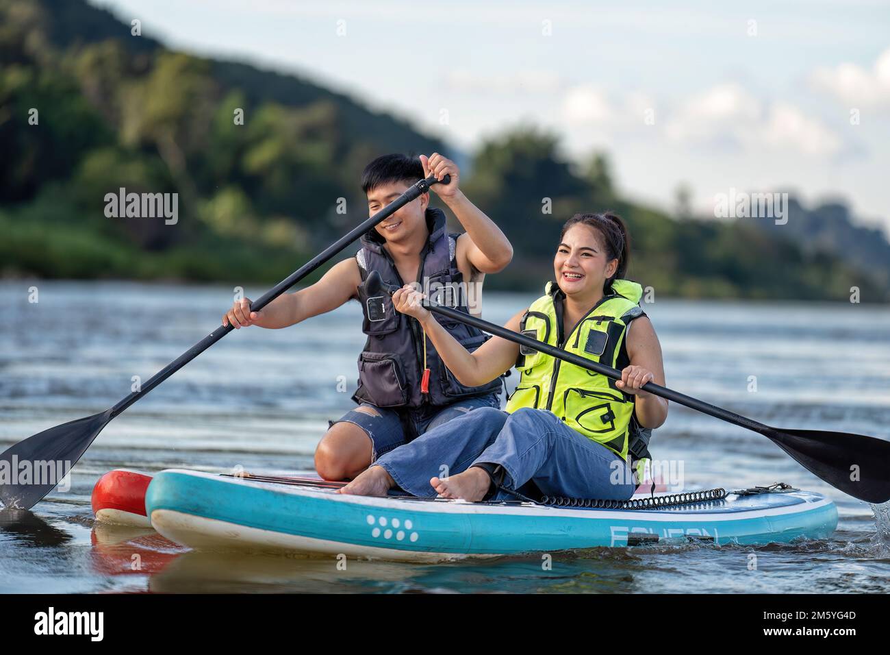 On summer holiday love couple relax sail sup board surf on river on ...