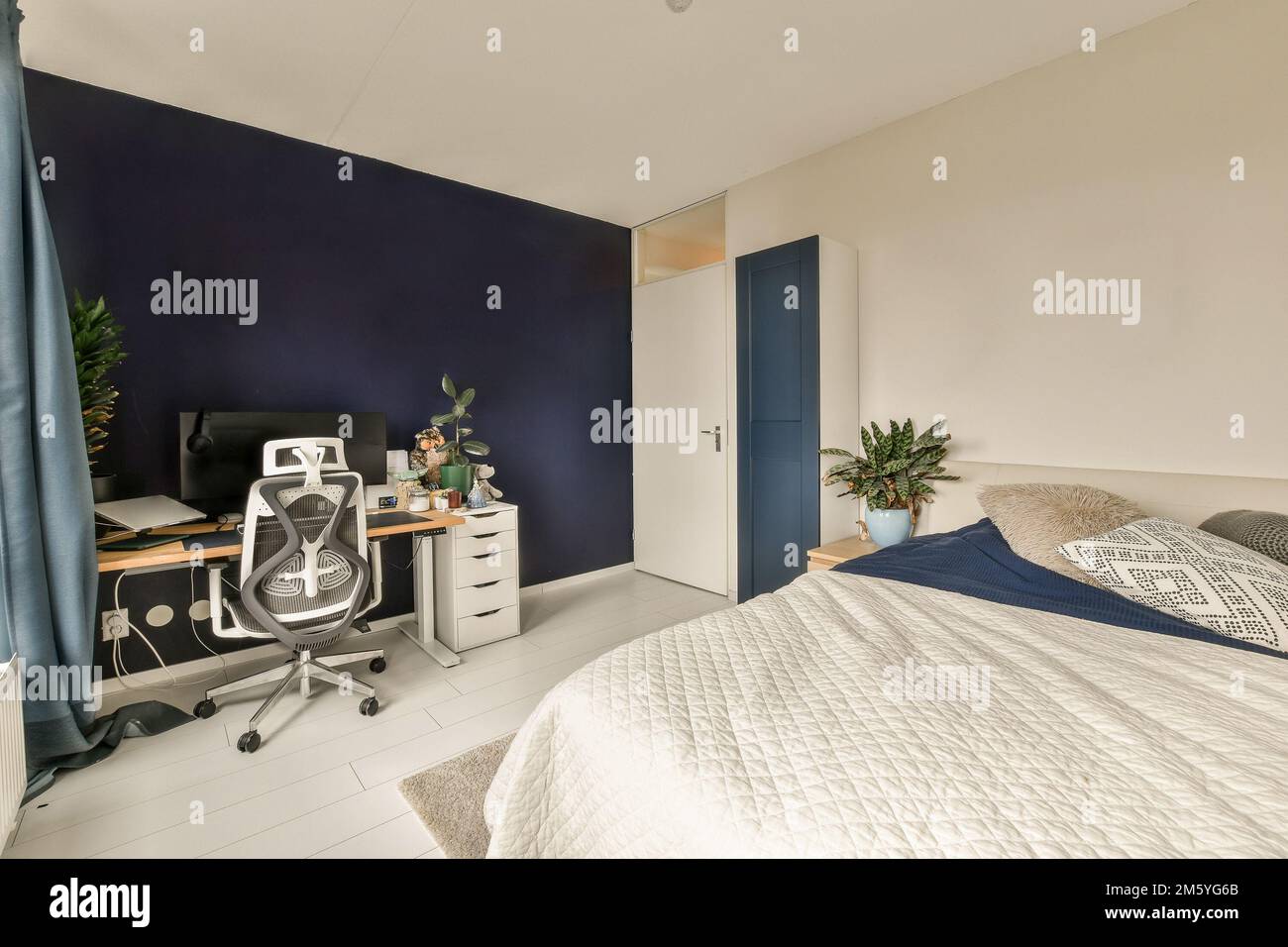 a bedroom with a bed, desk and computer monitor on the wall in front of ...