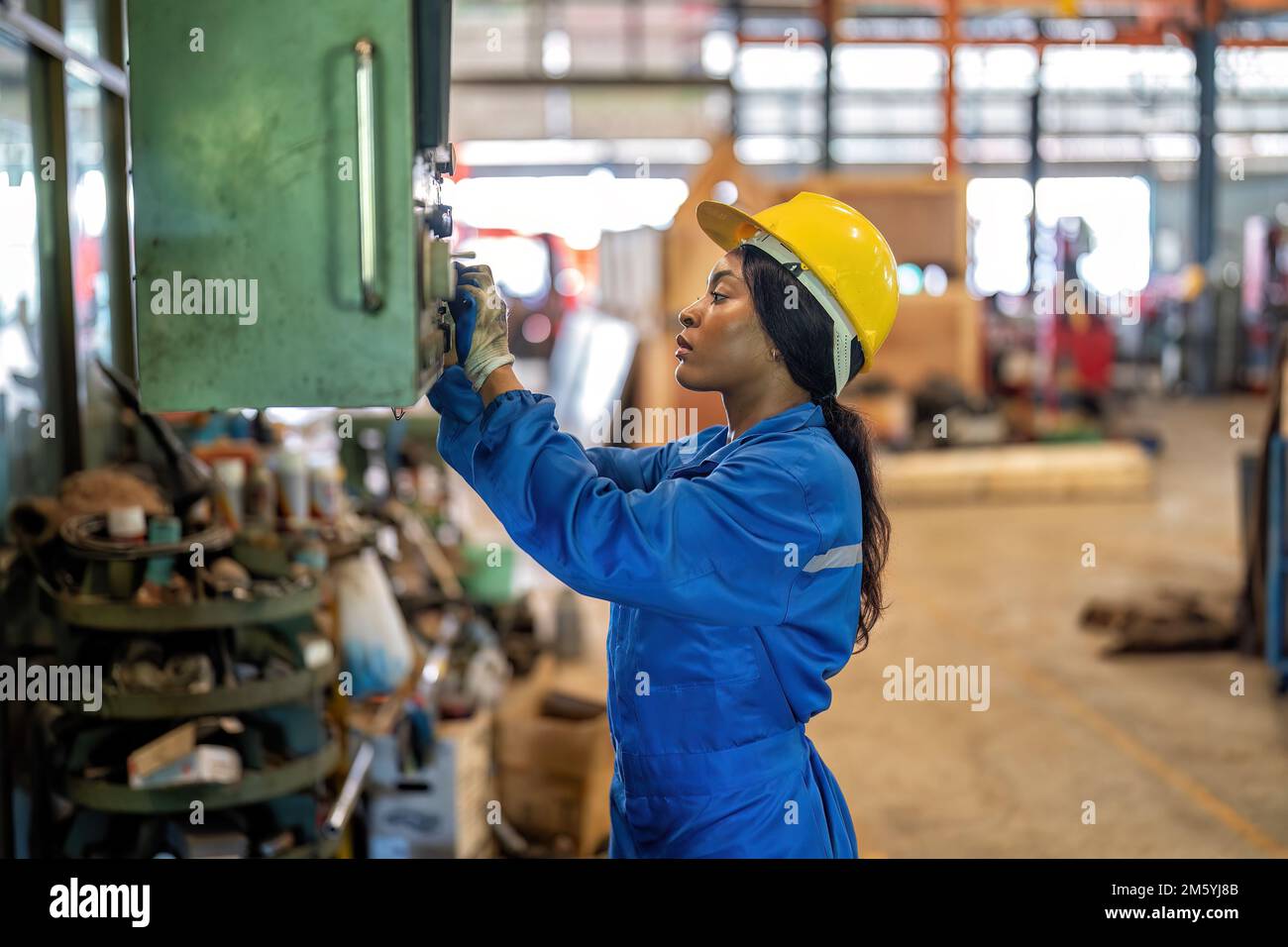 Mechanical woman in uniform working in machinery shop trouble shooting ...