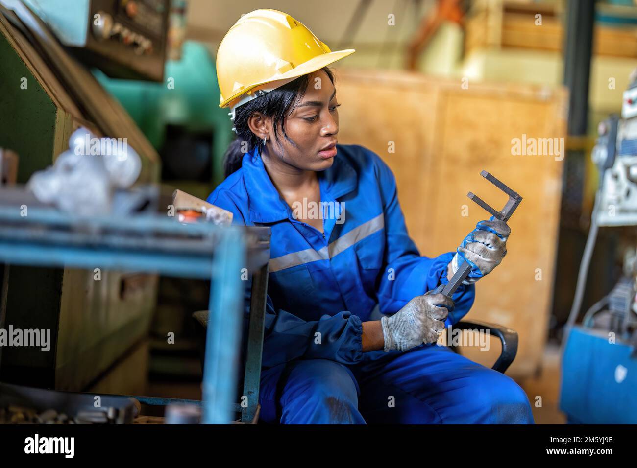 Mechanical girl in uniform on break time sitting check F wrench and heavy machinery in ...