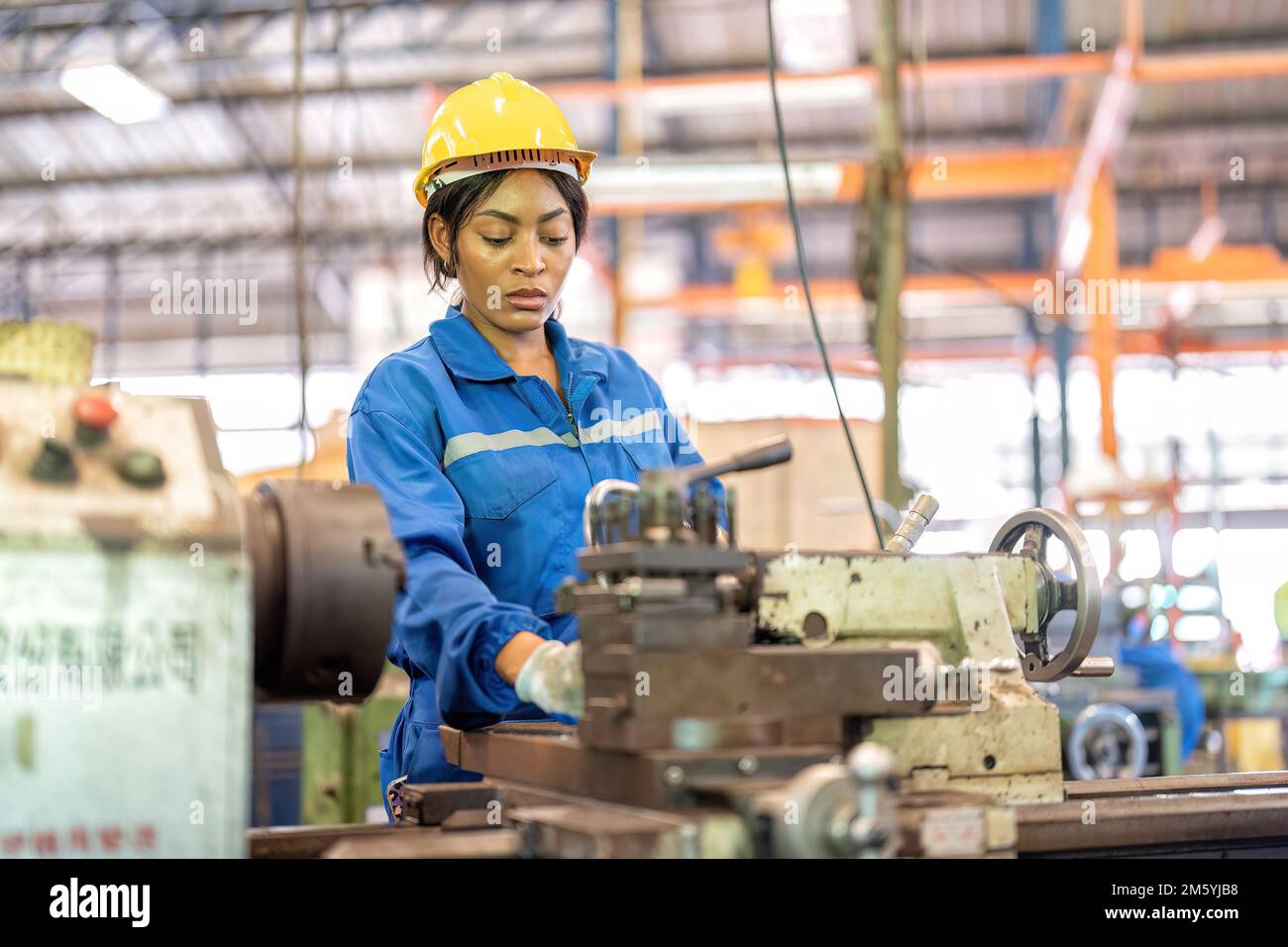 Woman worker in uniform operating machine at factory concentrate on ...