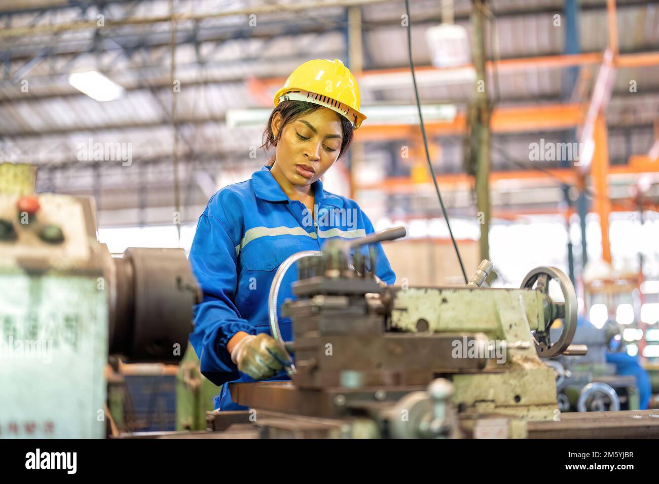 Woman worker in uniform operating machine at factory concentrate on ...