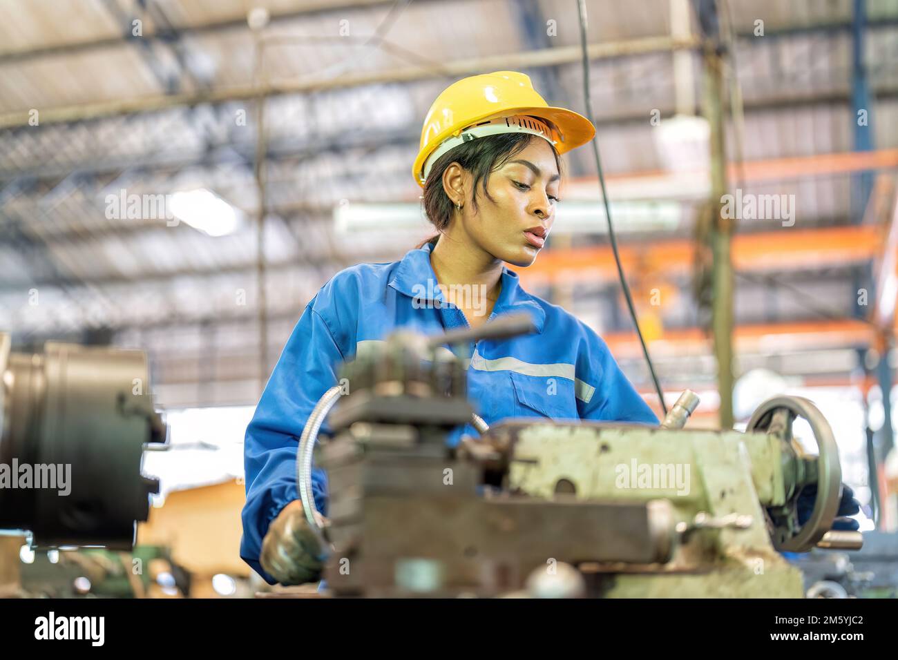 Woman worker in uniform operating machine at factory concentrate on ...