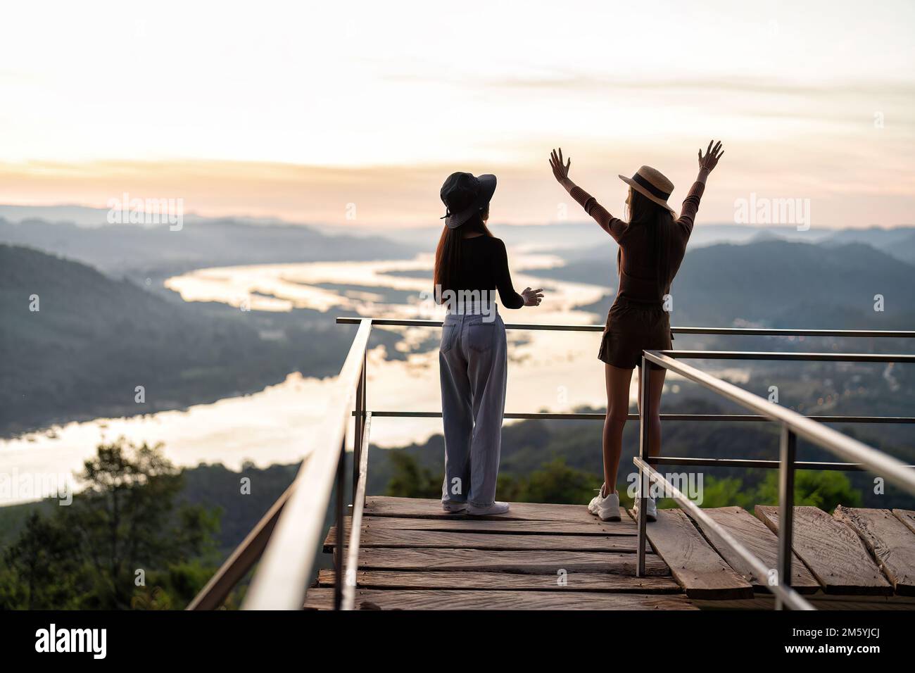 Sunrise morning 2 traveler girls stand on mountain view platform look ...