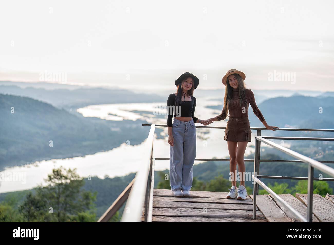 Sunrise morning 2 traveler girls stand on mountain view platform look ...