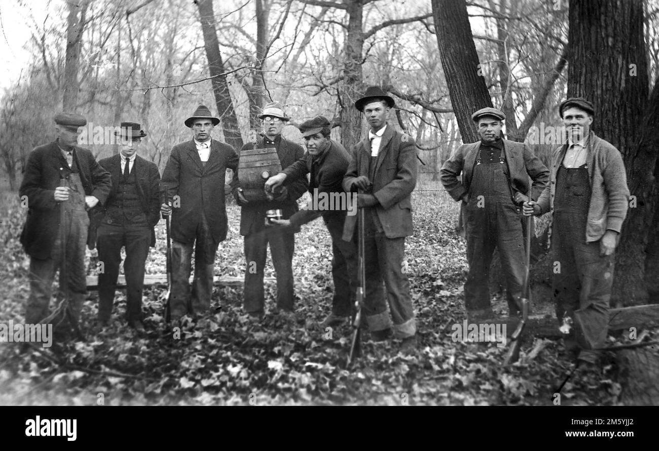 A group of hunters stand together with their guns and their beer barrel ...