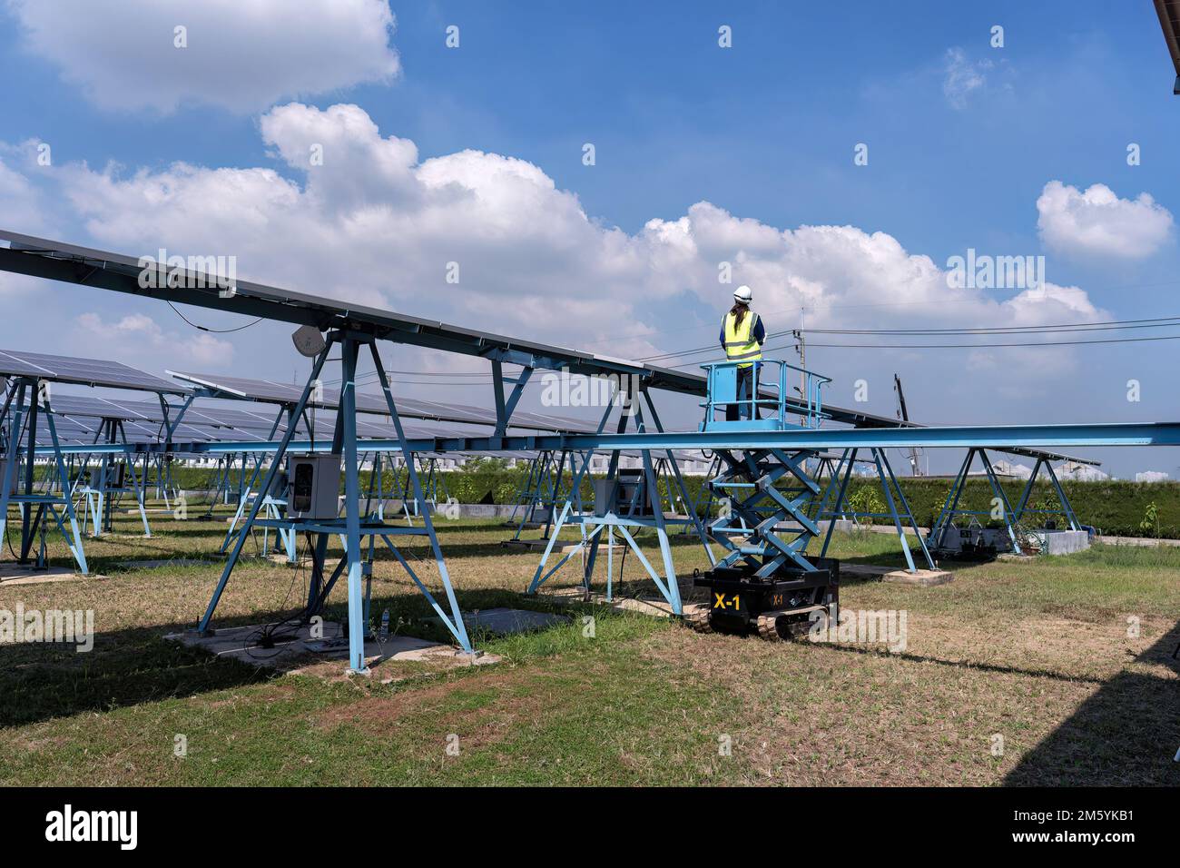 Maintenance engineer at solar farm stand on scissor lift hold check ...