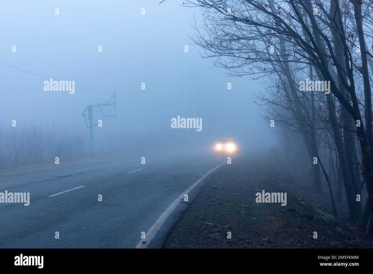 Vehicle coming out of a thick fog with switch on headlights Stock Photo ...
