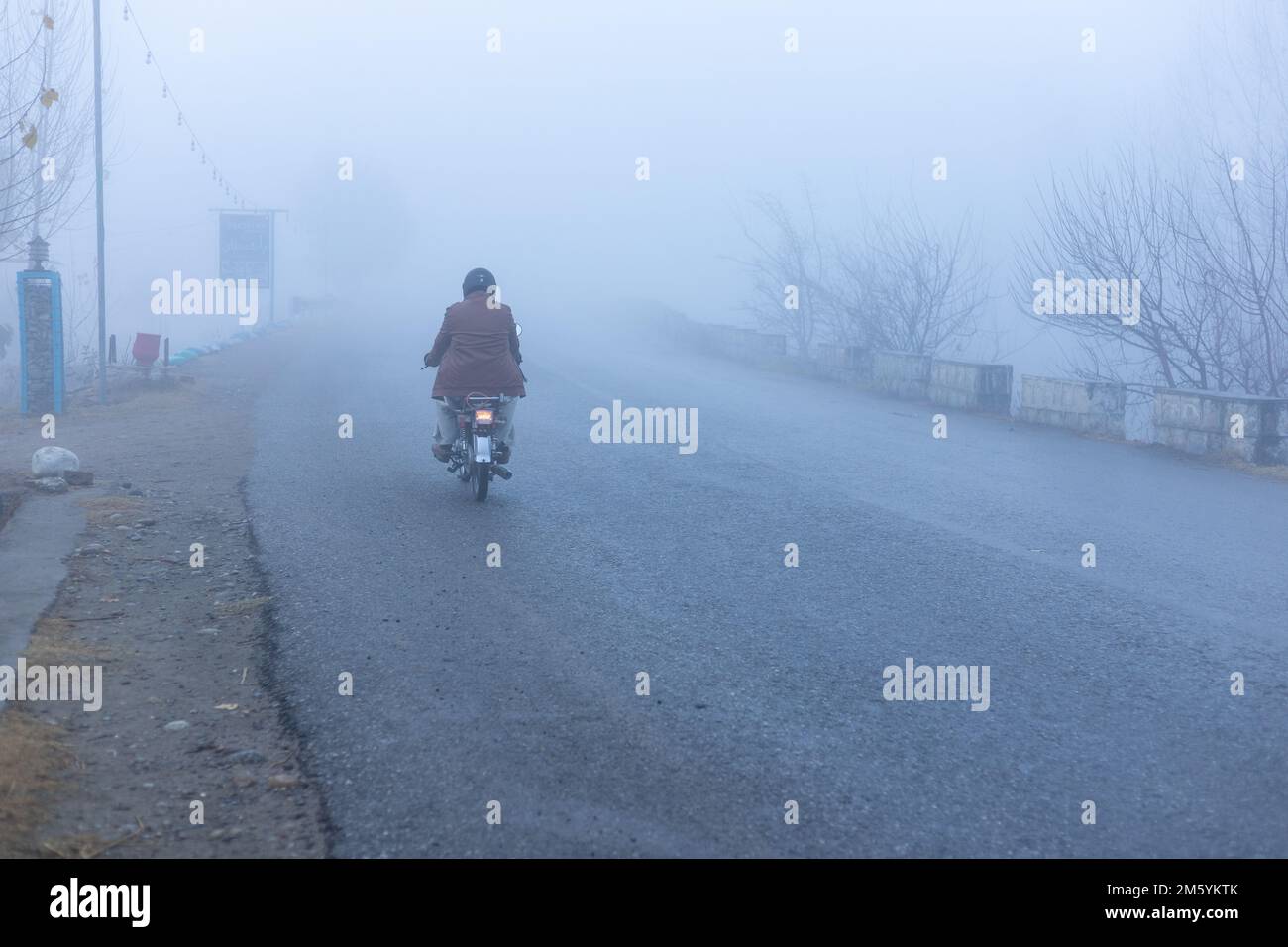Man riding on a bike going for work in thick fog in swat valley ...
