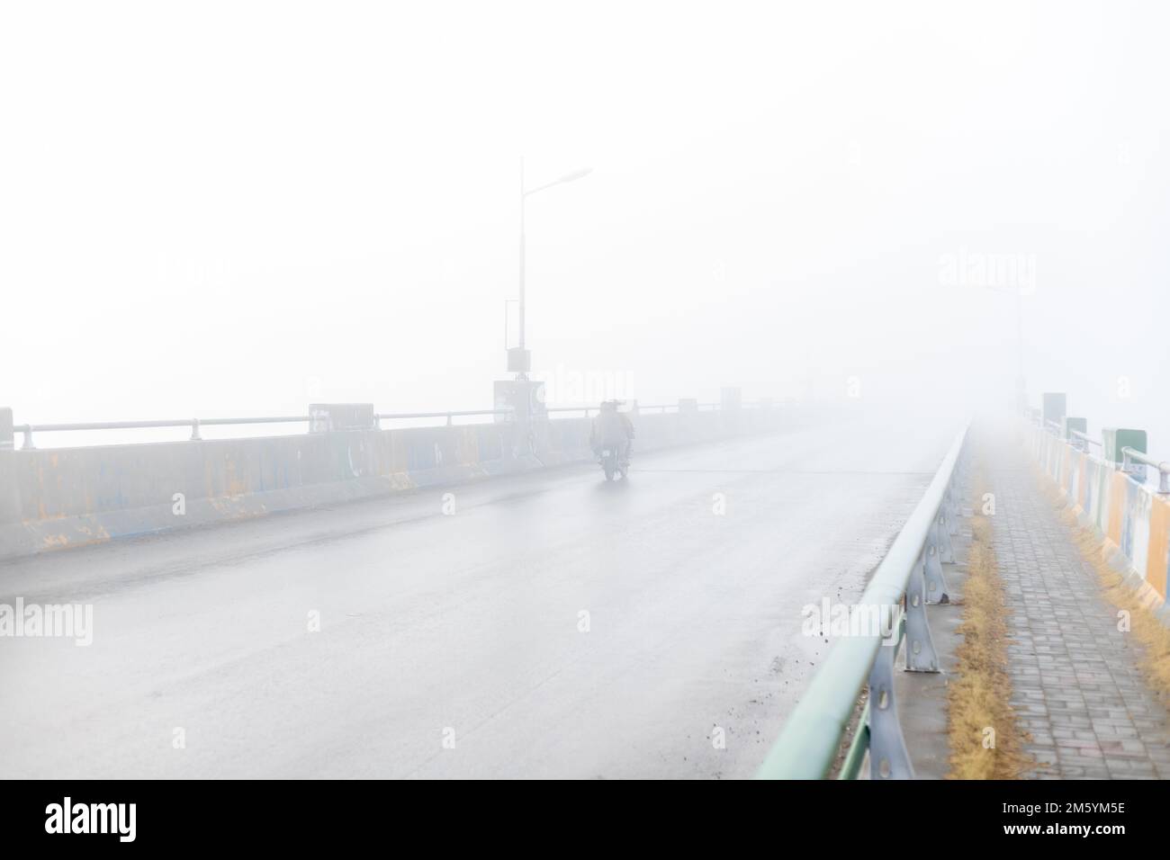 Motorcycles in dense fog crossing the bridge with low visibility Stock ...