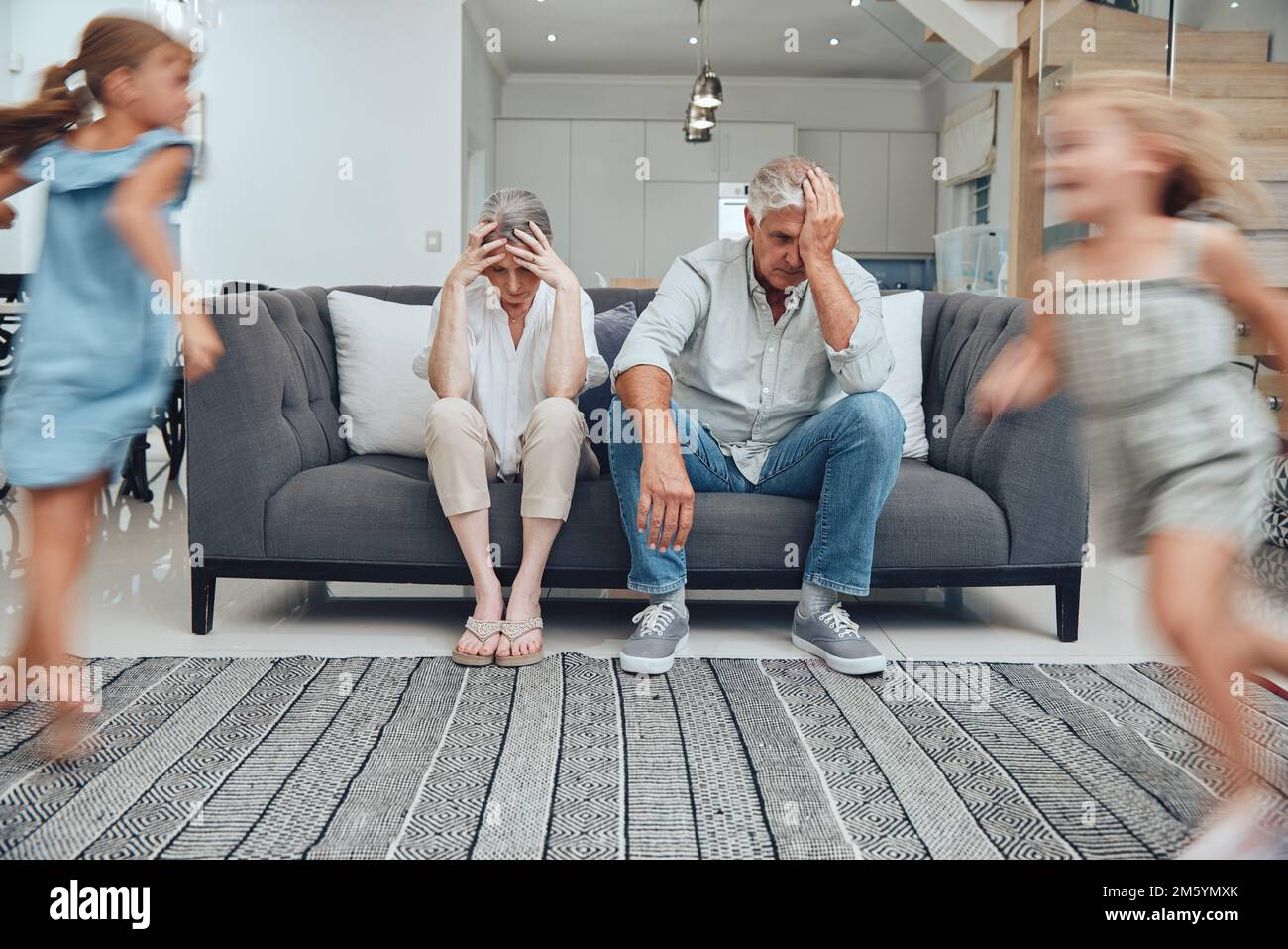 Burnout headache, children running and parents on living room sofa with ...