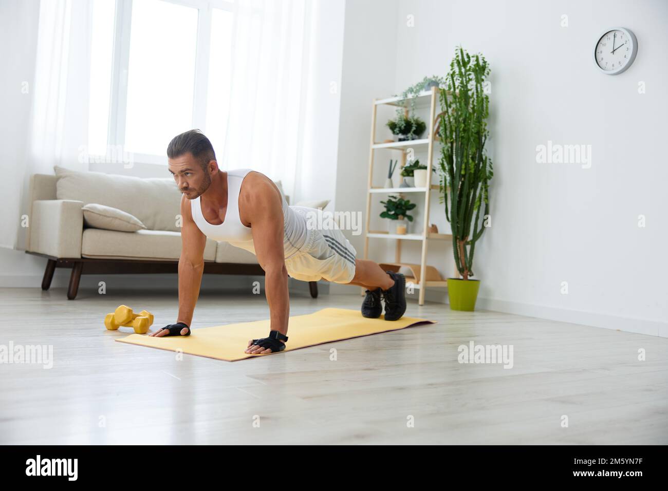 Man sports home training on the floor on a mat with dumbbells ...