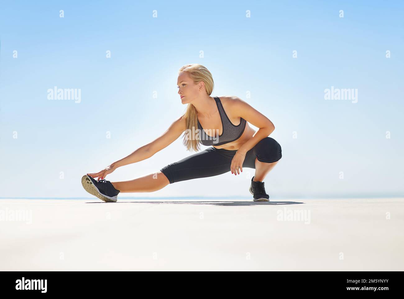 Stretching out her leg muscles. Full length shot of a young woman ...