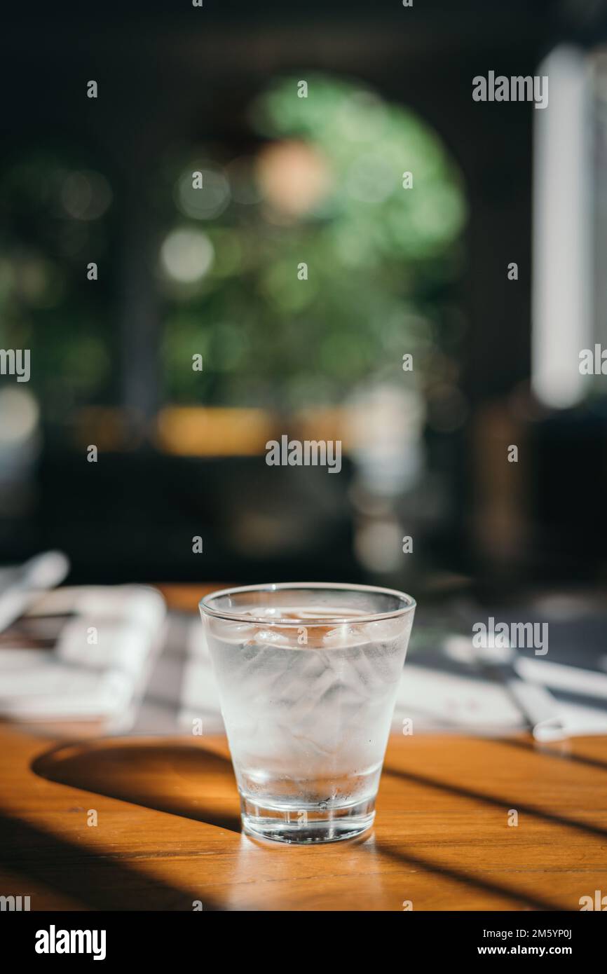 Clear Iced water glass on cafe wooden table with sunlight Stock Photo - Alamy