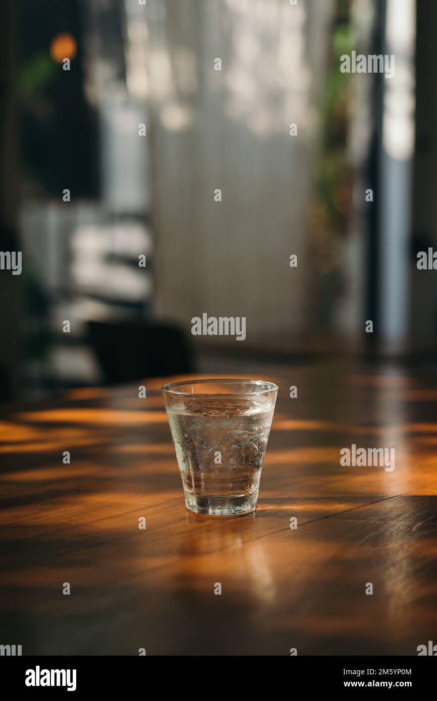 Clear Iced water glass on cafe wooden table with sunlight Stock Photo - Alamy