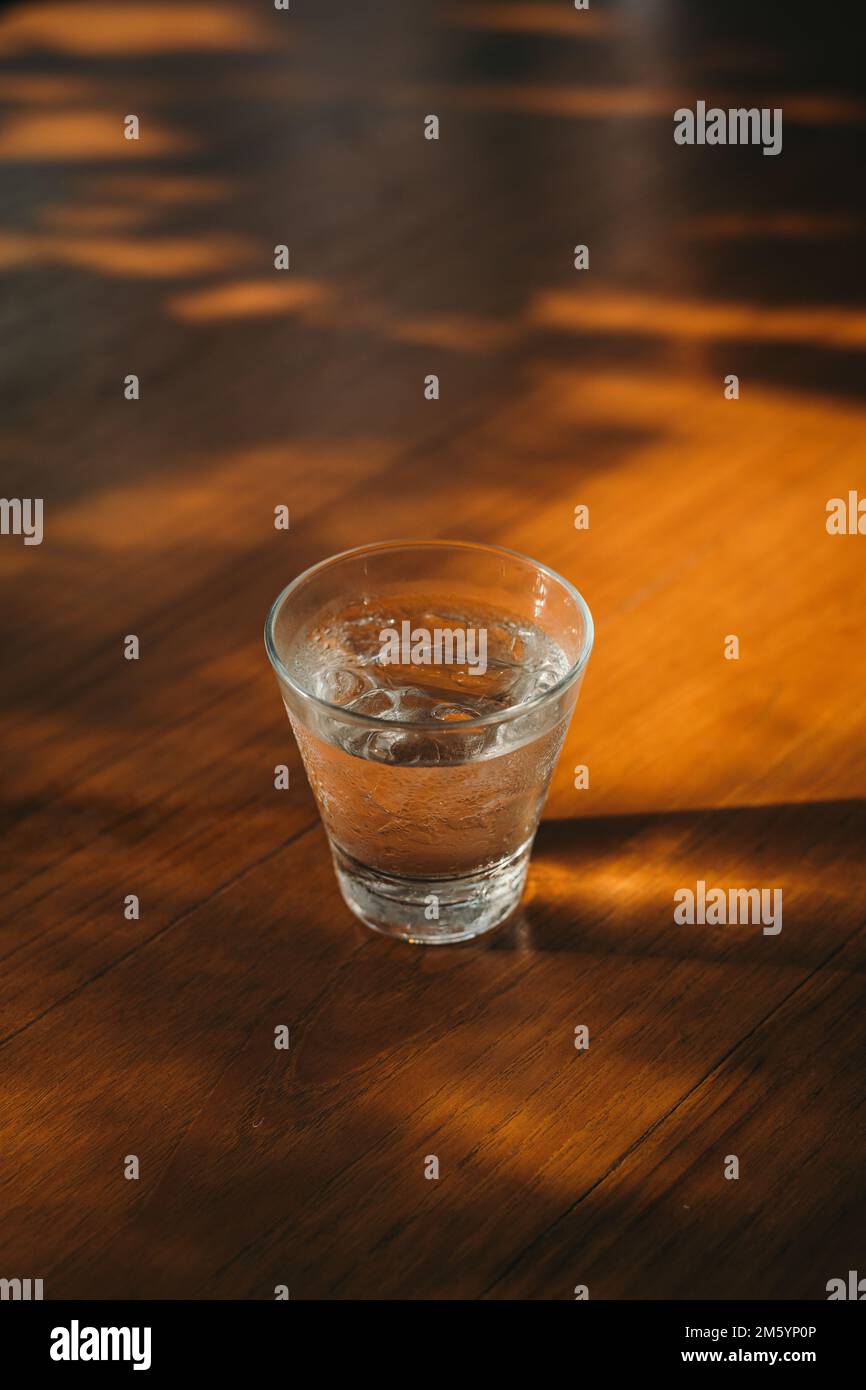 Clear Iced water glass on cafe wooden table with sunlight Stock Photo - Alamy