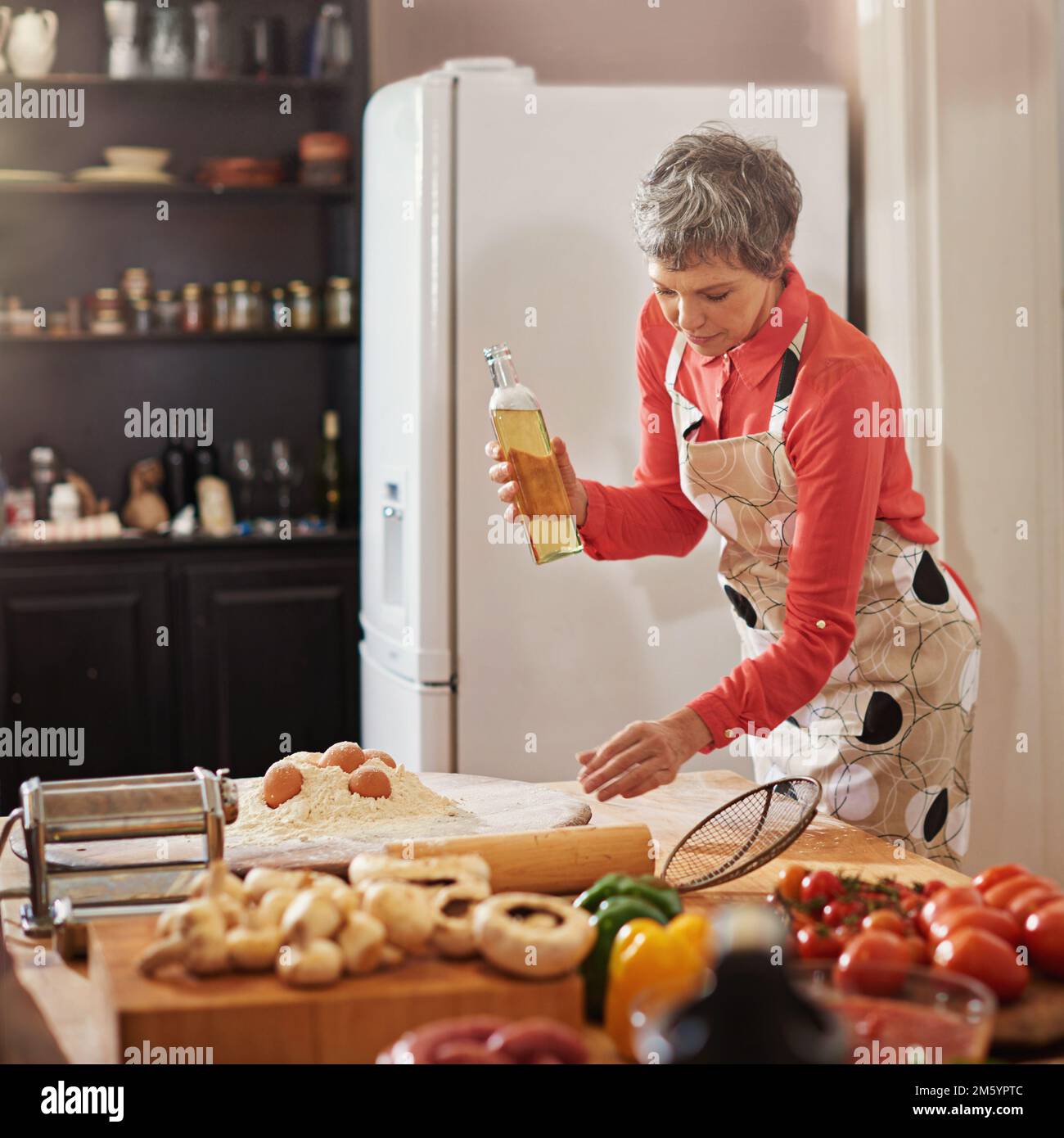Keep calm and use olive oil. a woman cooking in her kitchen Stock Photo ...