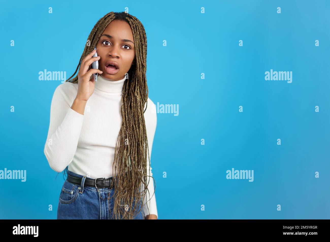 African woman with an expression of disbelief talking with mobile Stock ...