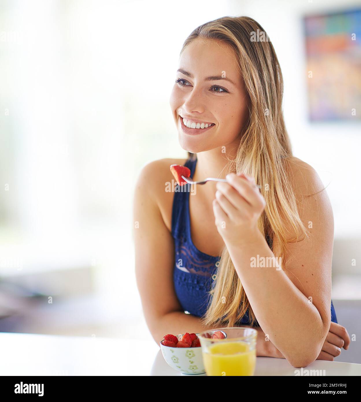 Have a fruitful day. a young woman eating a bowl of strawberries at ...
