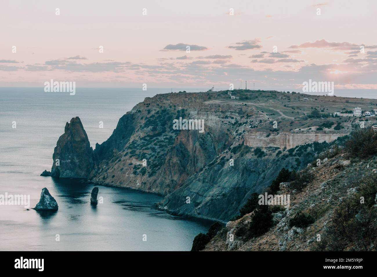 A red burning sunset over the sea with rocky volcanic cliff. Abstract ...