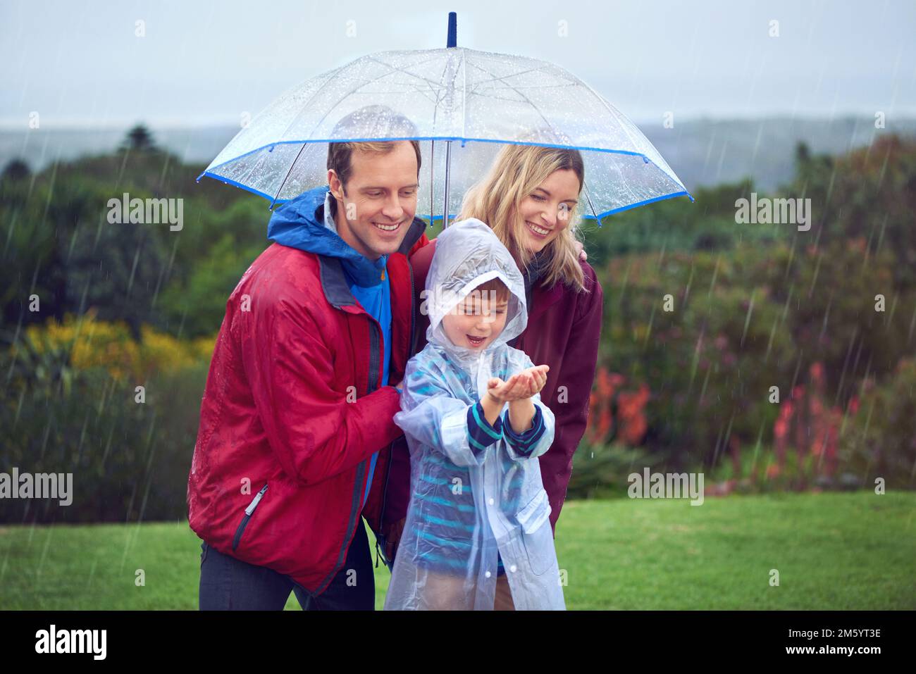 Rain, rain and rain some more. Cropped portrait of a family of three ...