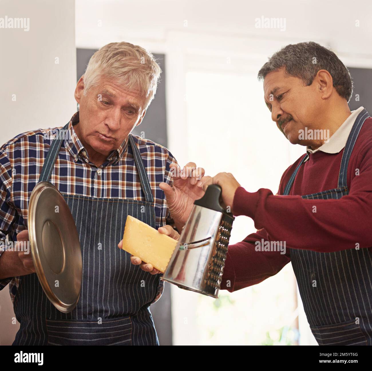 Dont be scared to add a little more cheese. two senior men cooking in ...