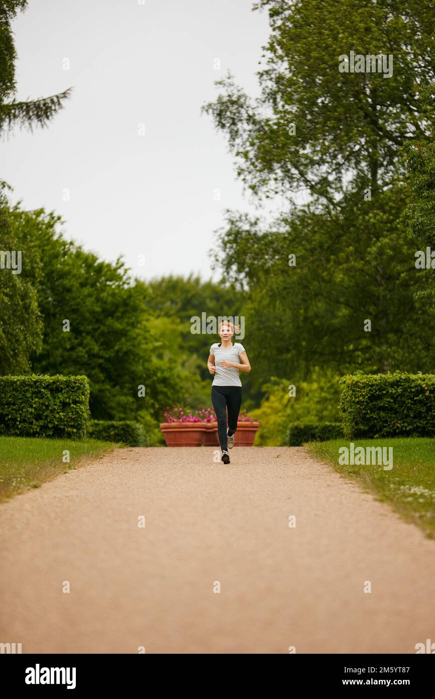 Taking the run one stride at a time. a woman jogging down a foothpath ...
