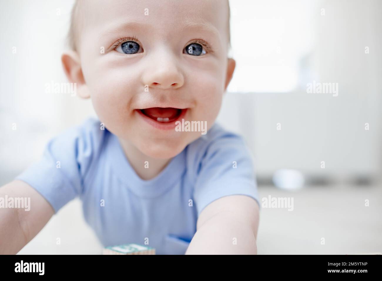 Exploring the living room. A sweet little boy smiling while lying on ...