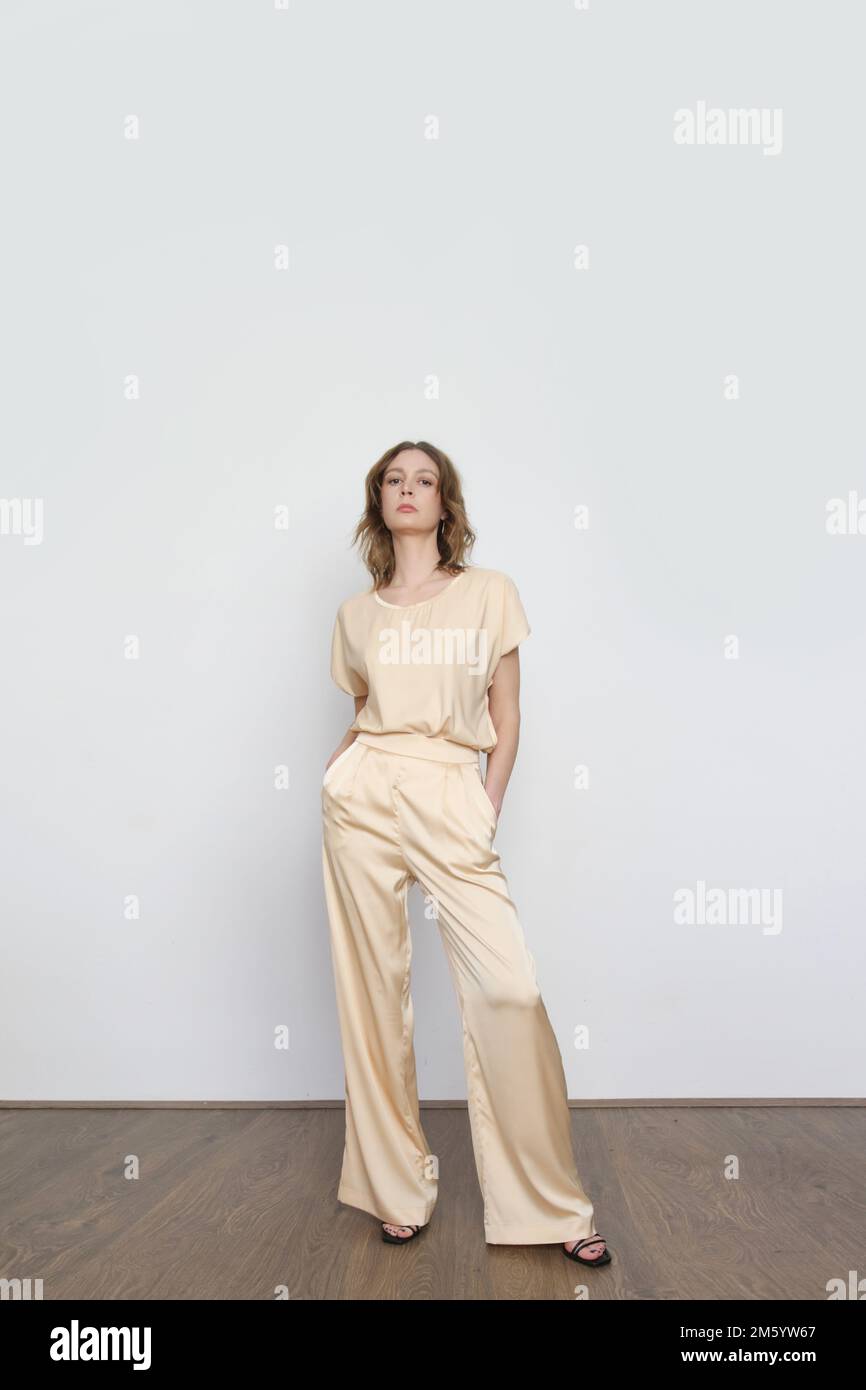 Serie of studio photos of young female model in beige silk outfit Stock ...