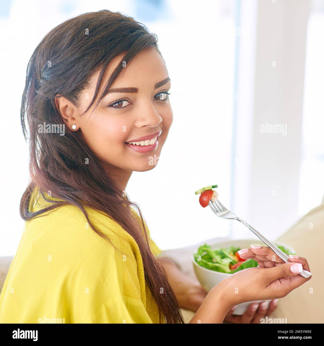 Staying on the healthy side. a young woman eating a salad at home Stock ...