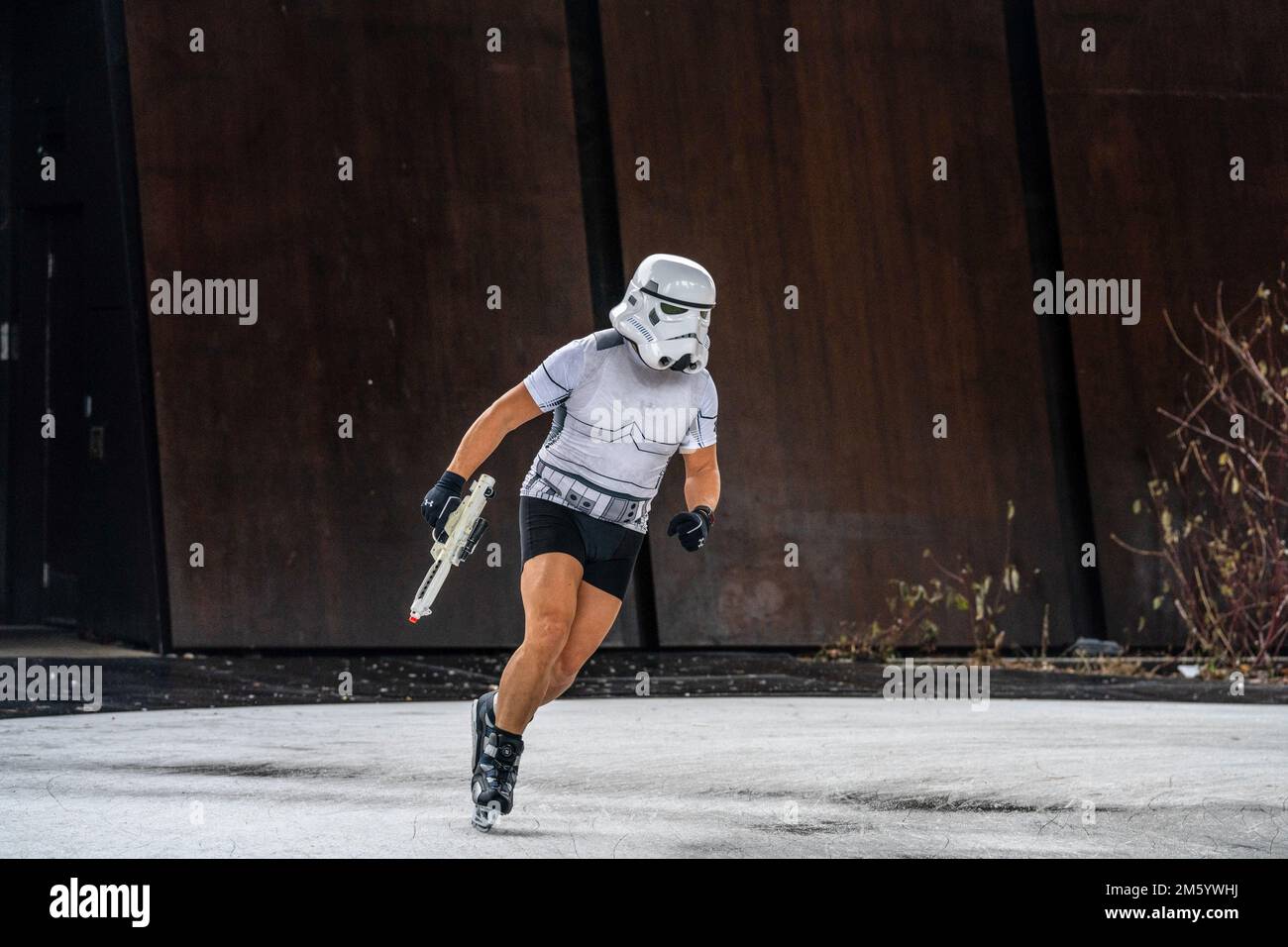 An ice skater wearing a Storm Trooper helmet and holding a toy blaster ...