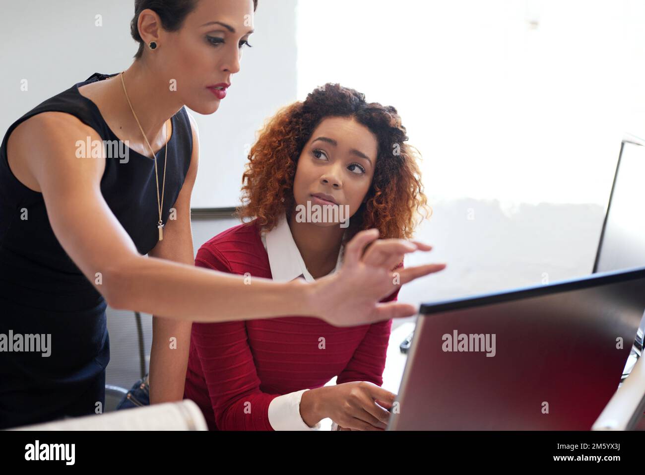 Getting valuable input from a colleague. two businesswoman working ...