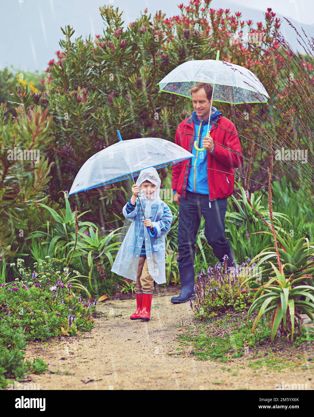 Rainy days. Full length shot of a father and his son walking outside in ...