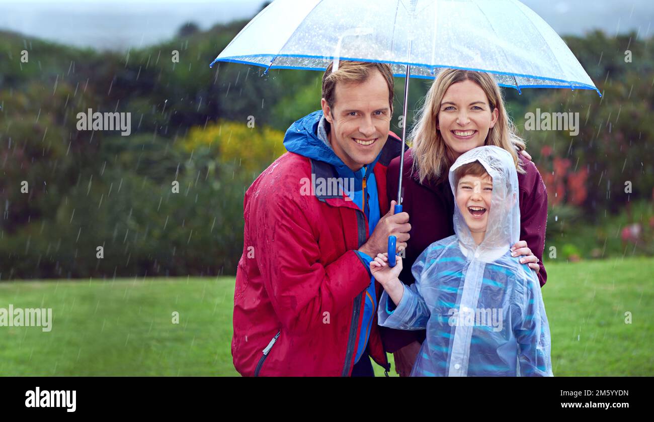 Wet days are wonderful. Cropped portrait of a family of three standing outside in the rain Stock ...