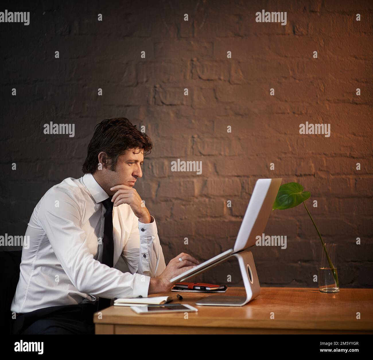 Working late into the night...a businessman working on his laptop after ...