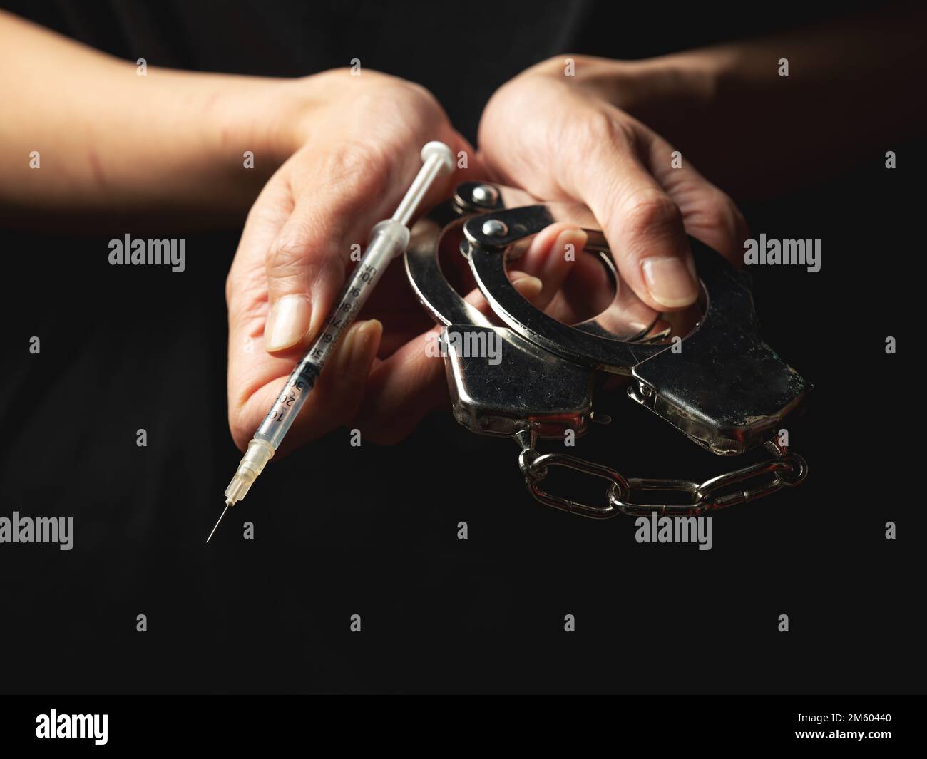 Handcuffs on wrist, drug syringe Stock Photo - Alamy