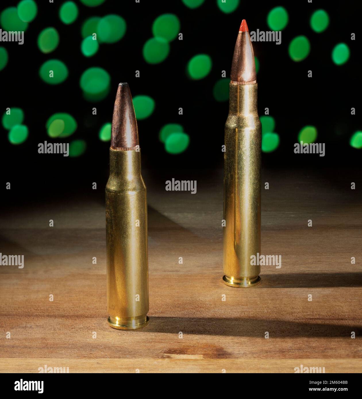 Large and smaller rifle ammunition on wood with green Christmas lights ...