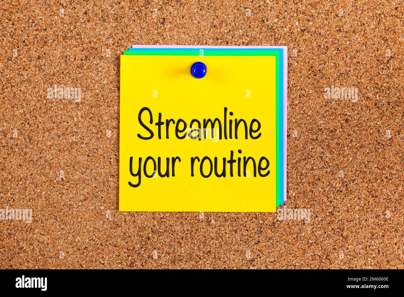 Yellow paper note with words Streamline Your Routine on a corkboard ...